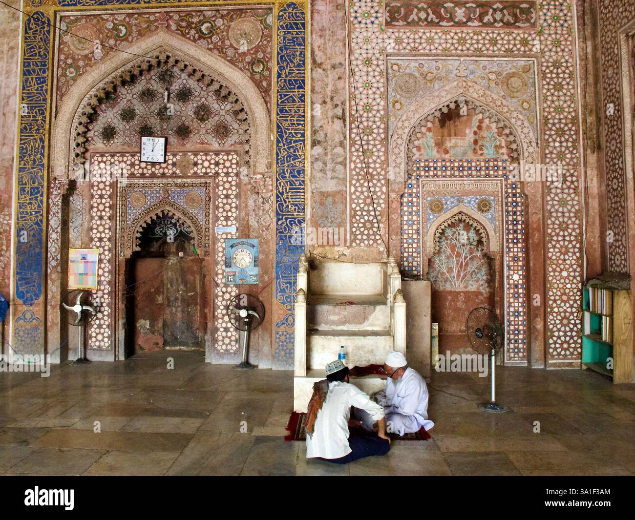 Two men talk near the intricately decorated mihrab and minbar of Jama ...