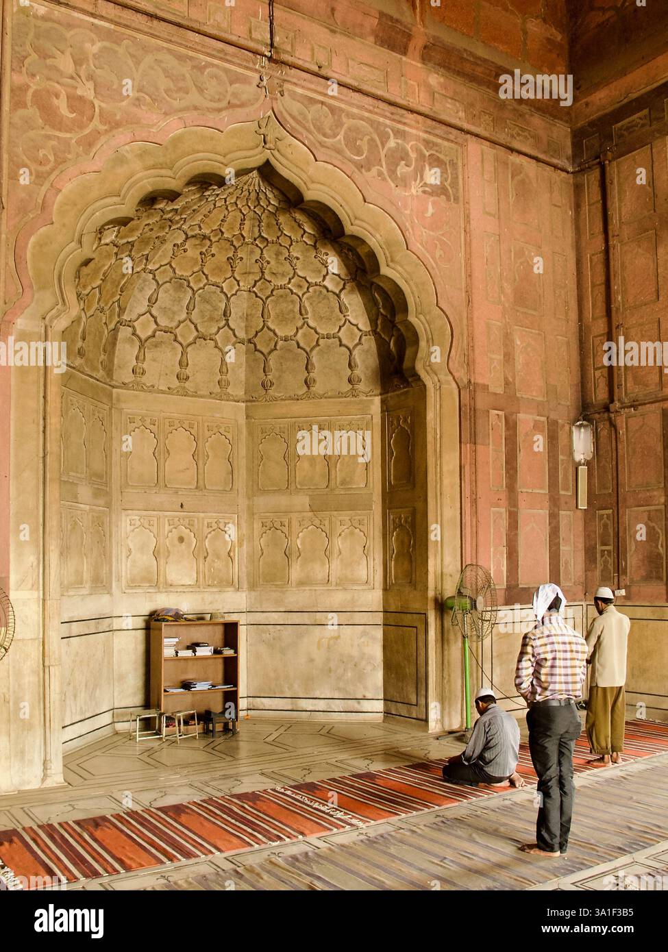 Men pray before the intricately carved mihrab in the inner prayer hall ...