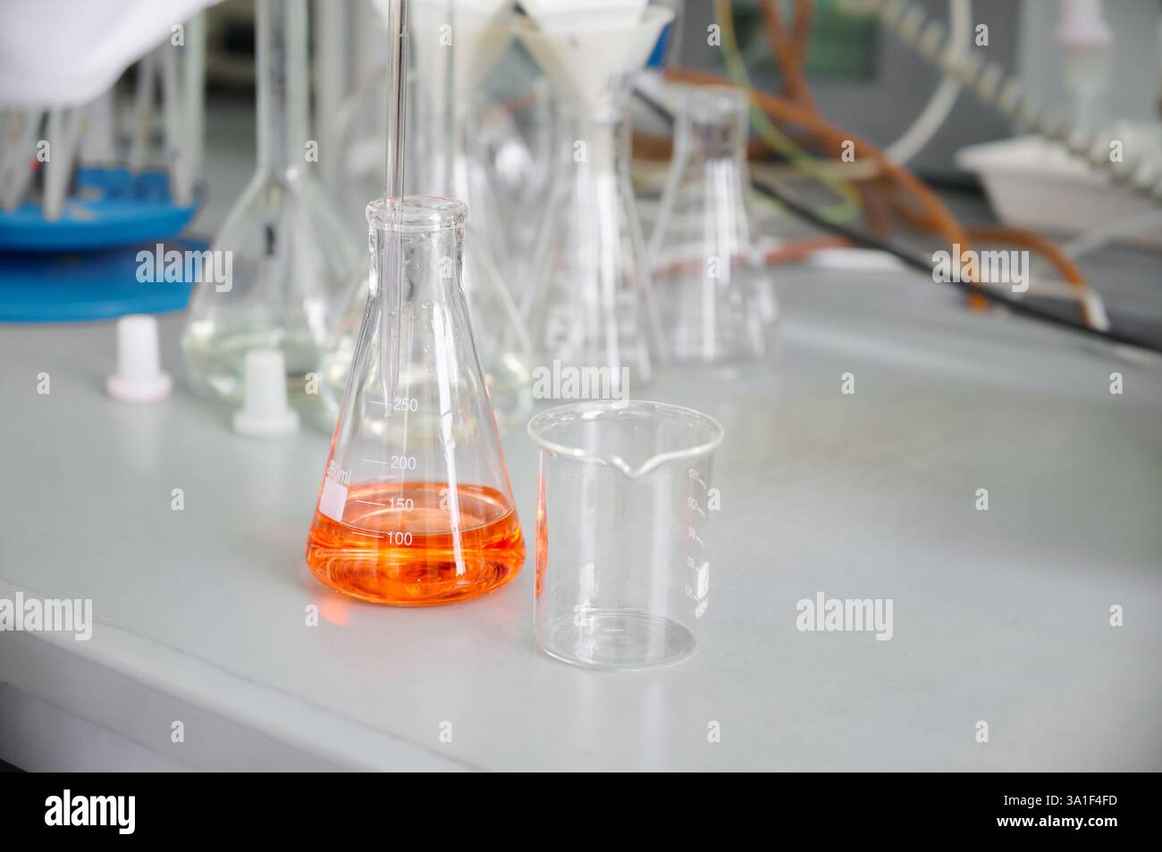 Laboratory experiment showing orange liquid in a flask beside a clear ...