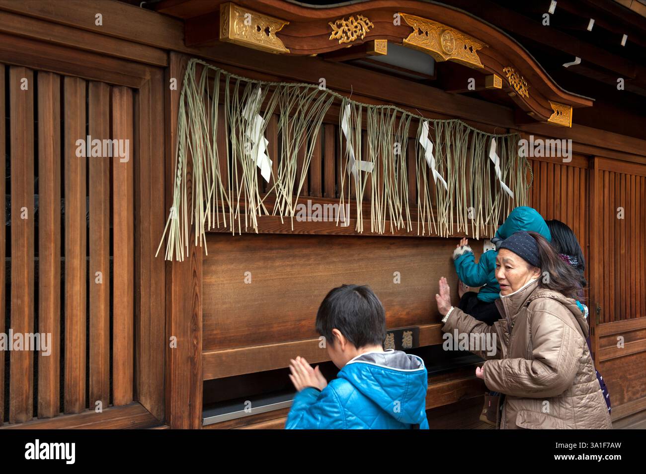 Worshipers touch, tap and pray at a wooden panel at Ebisu Jinja shrine ...