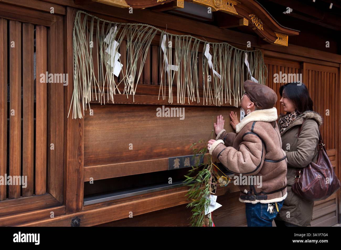 Worshipers touch, tap and pray at a wooden panel at Ebisu Jinja shrine ...