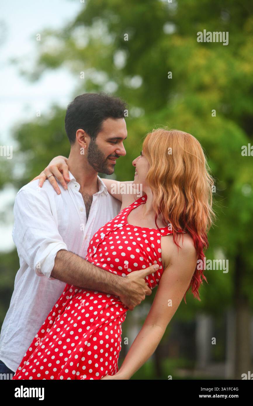portrait of mid adult cheerful mixed-race couple in love in the park on ...
