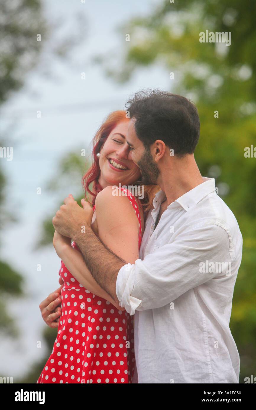 portrait of mid adult cheerful mixed-race couple in love in the park on ...