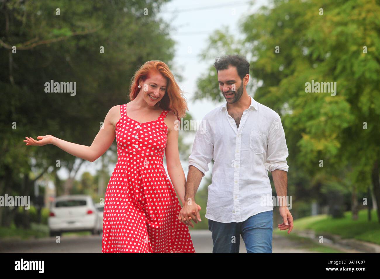 cheerful mid adult mixed-race couple in love walking and talking in a ...