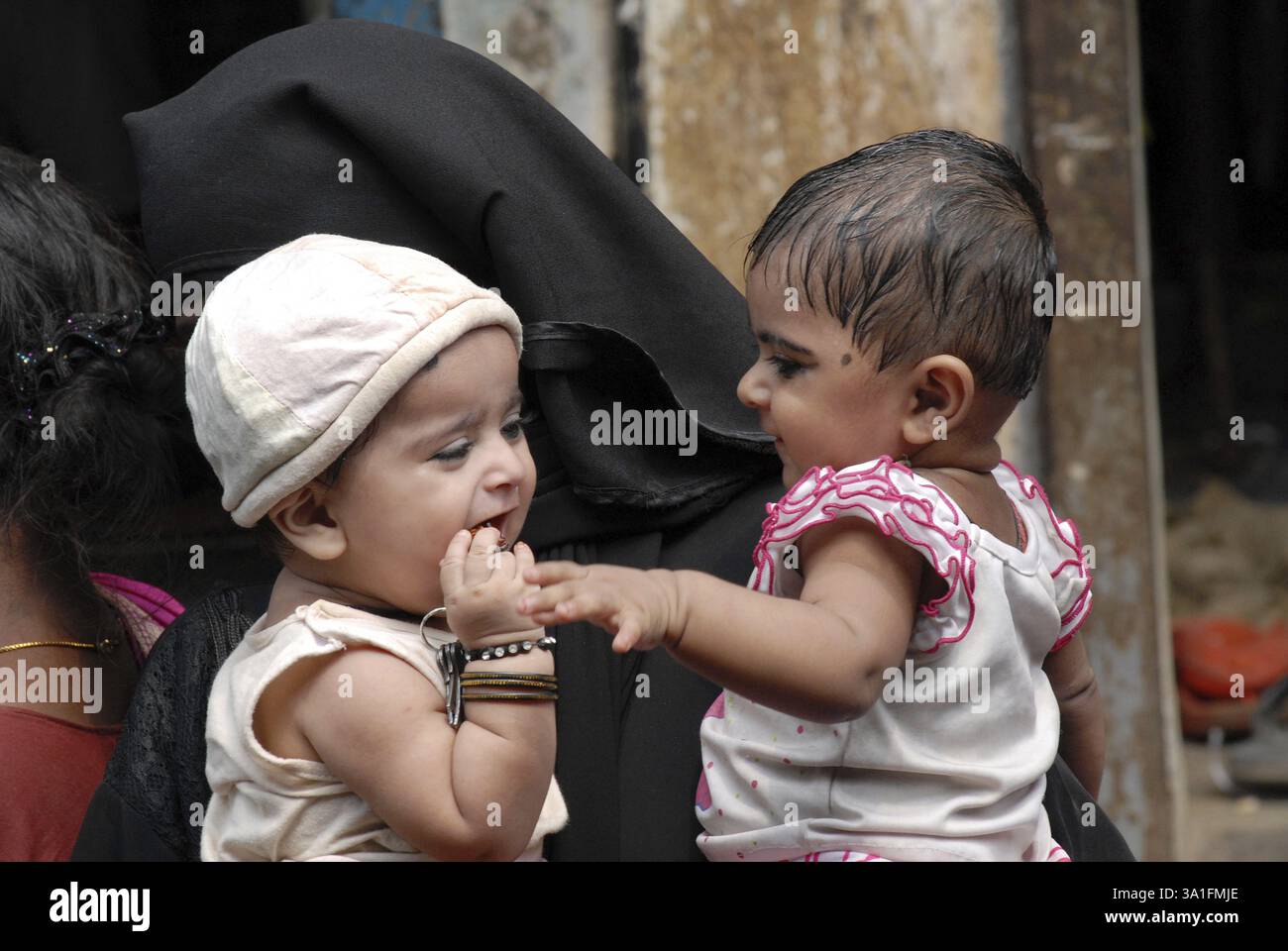 Muslim women stand in a queue with their children at a pulse polio ...
