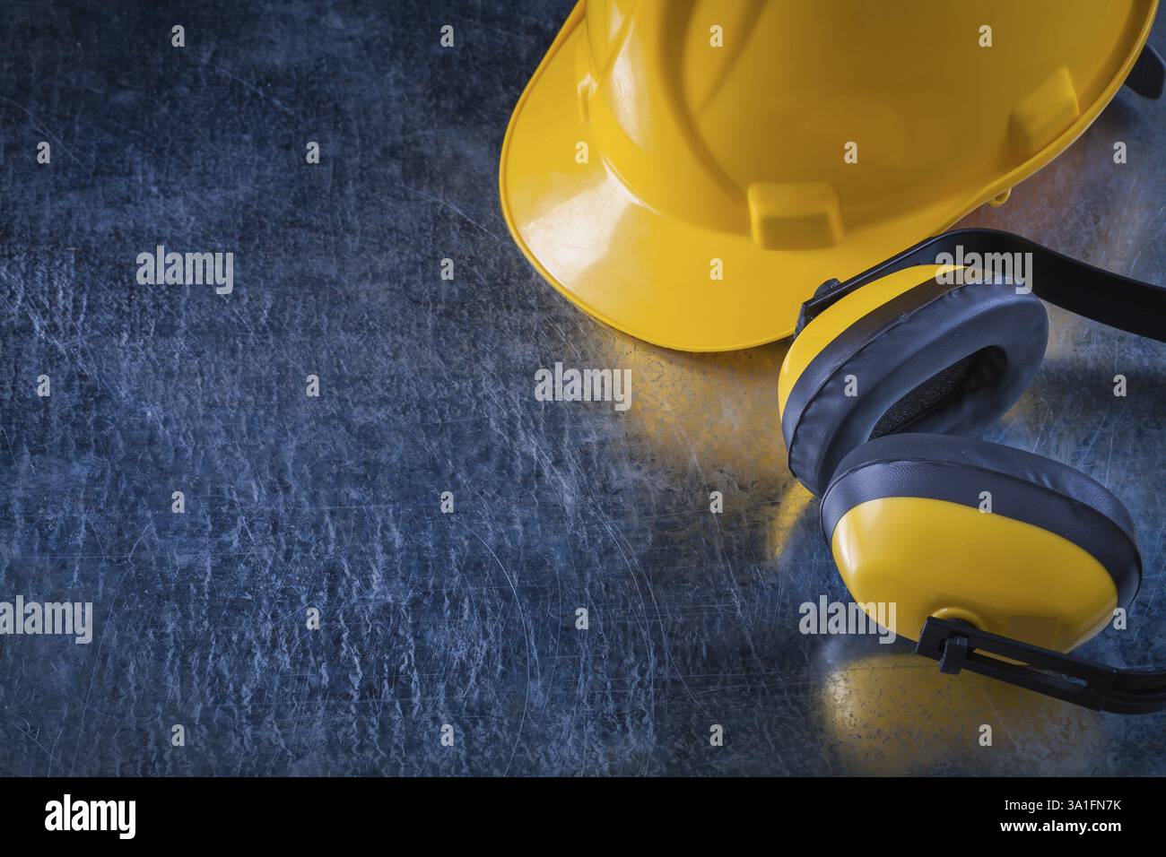 Noise insulation ear muffs and hard hat on scratched metallic ...