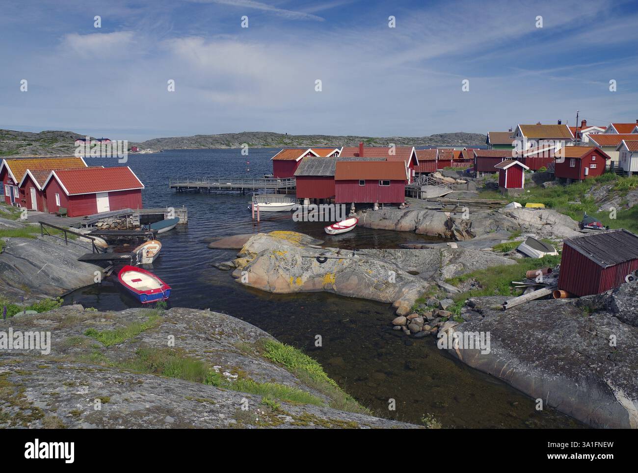 Coastal landscape with red wooden houses and boats, surrounded by rocks ...