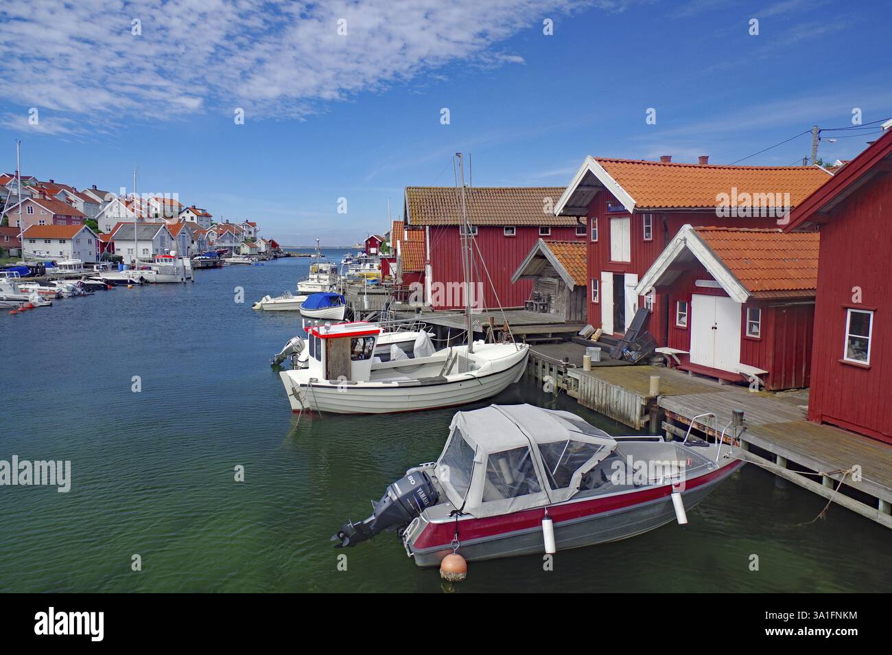 Boats in the harbour in front of red wooden houses on a summery day ...