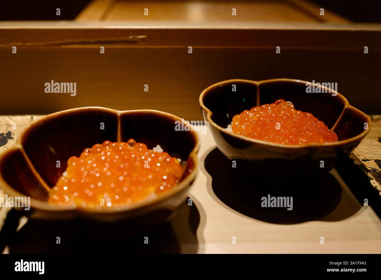 Two small glazed ceramic bowls of ikura don (salmon roe rice bowl ...