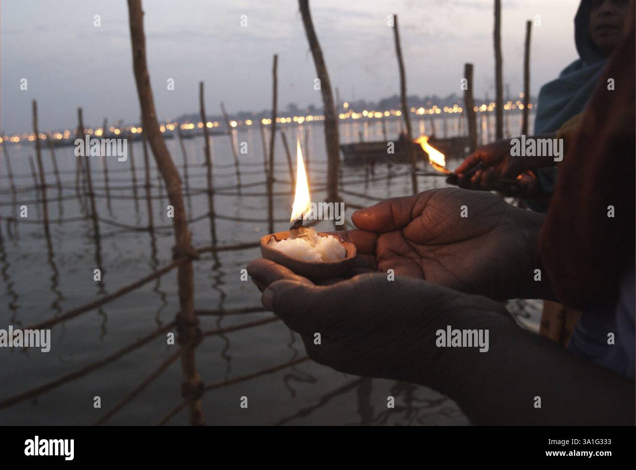 A devotee perform Ganga Aarti at the confluence of the Ganges, Yamuna ...