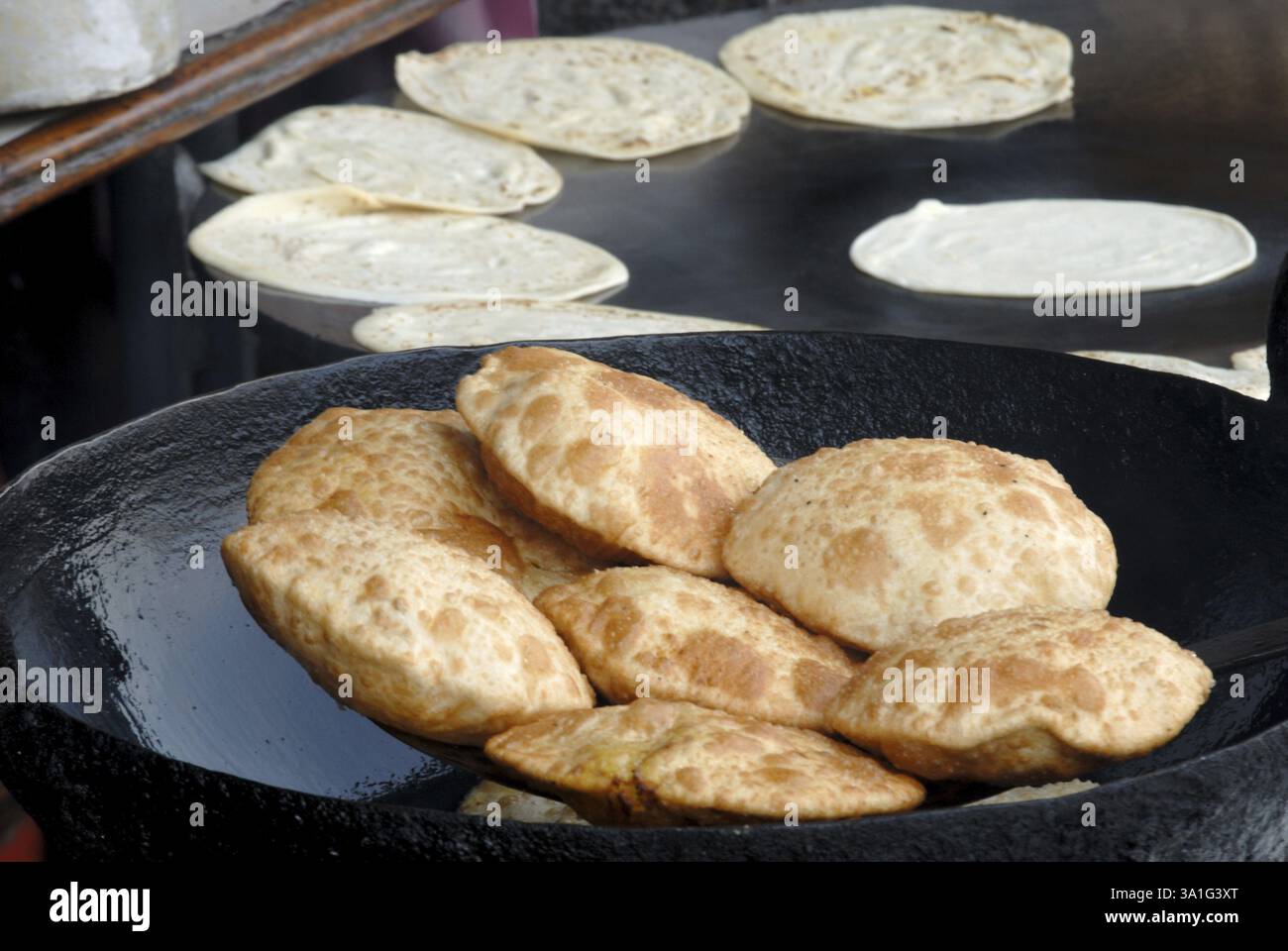Indian fast food puri frying in oil made maida flour in background roti ...