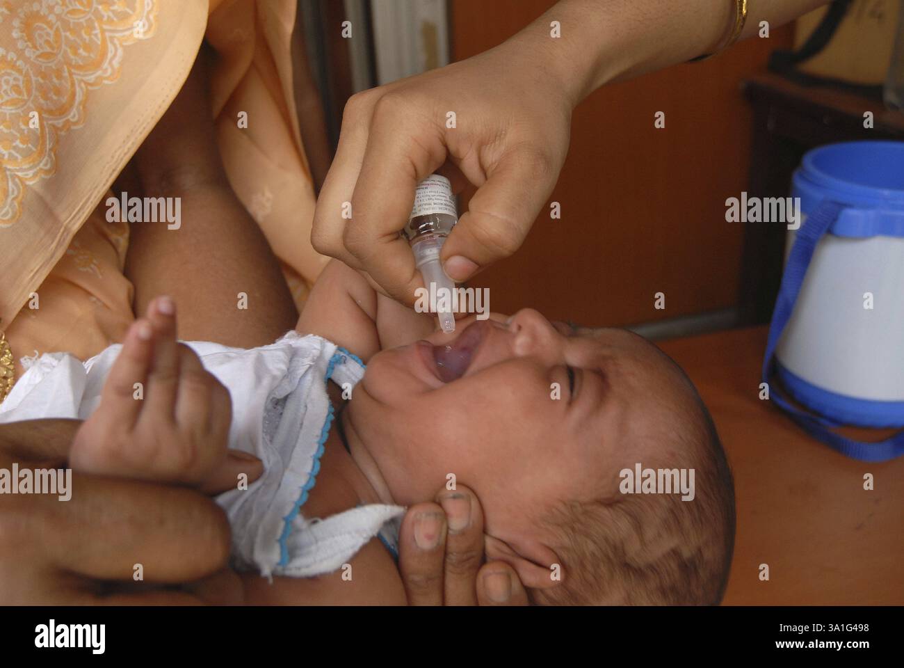 A woman holds her child in her hands to administer Polio vaccination ...