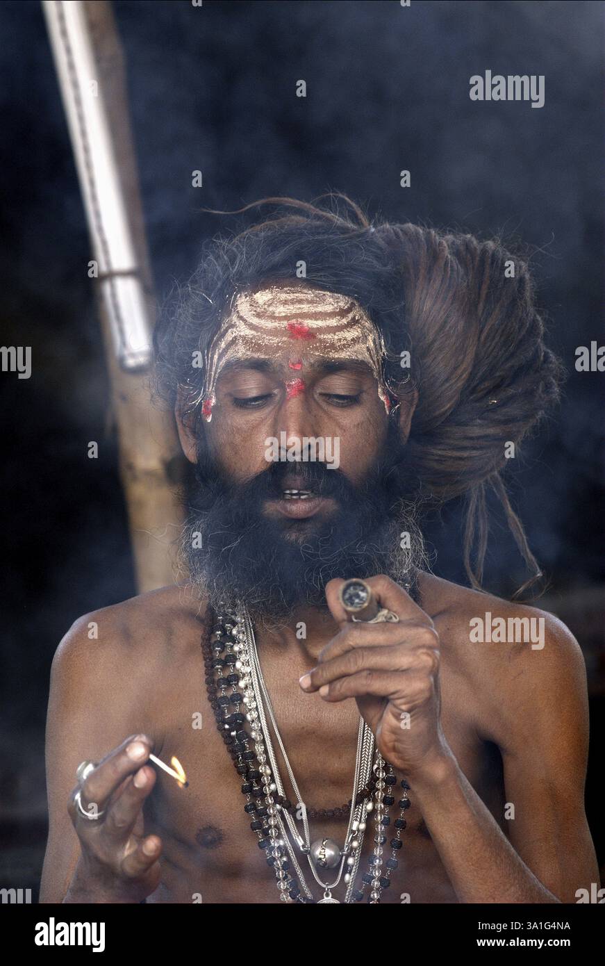 A sadhu from the Juna Akadha smoke opium at their camp during the Ardh ...
