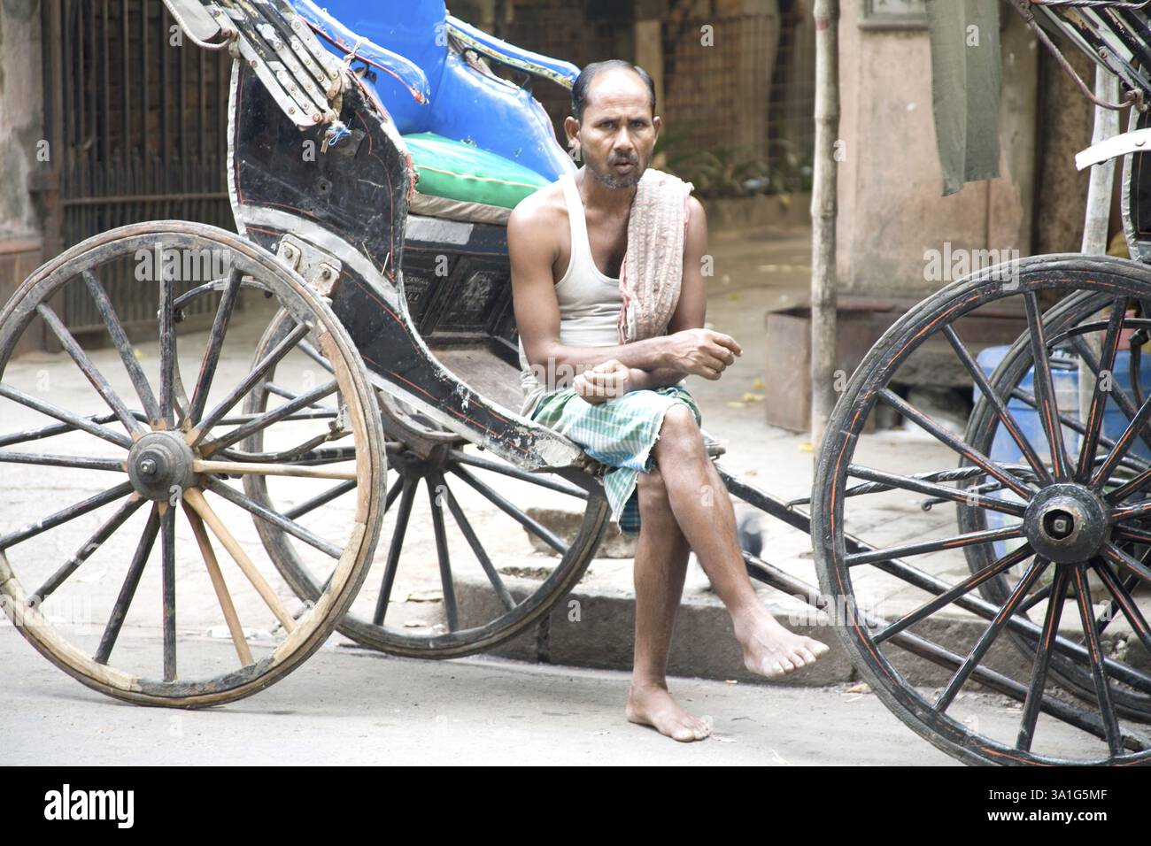 Manual labor hand rickshaw puller sitting in his vehicle, Park street ...