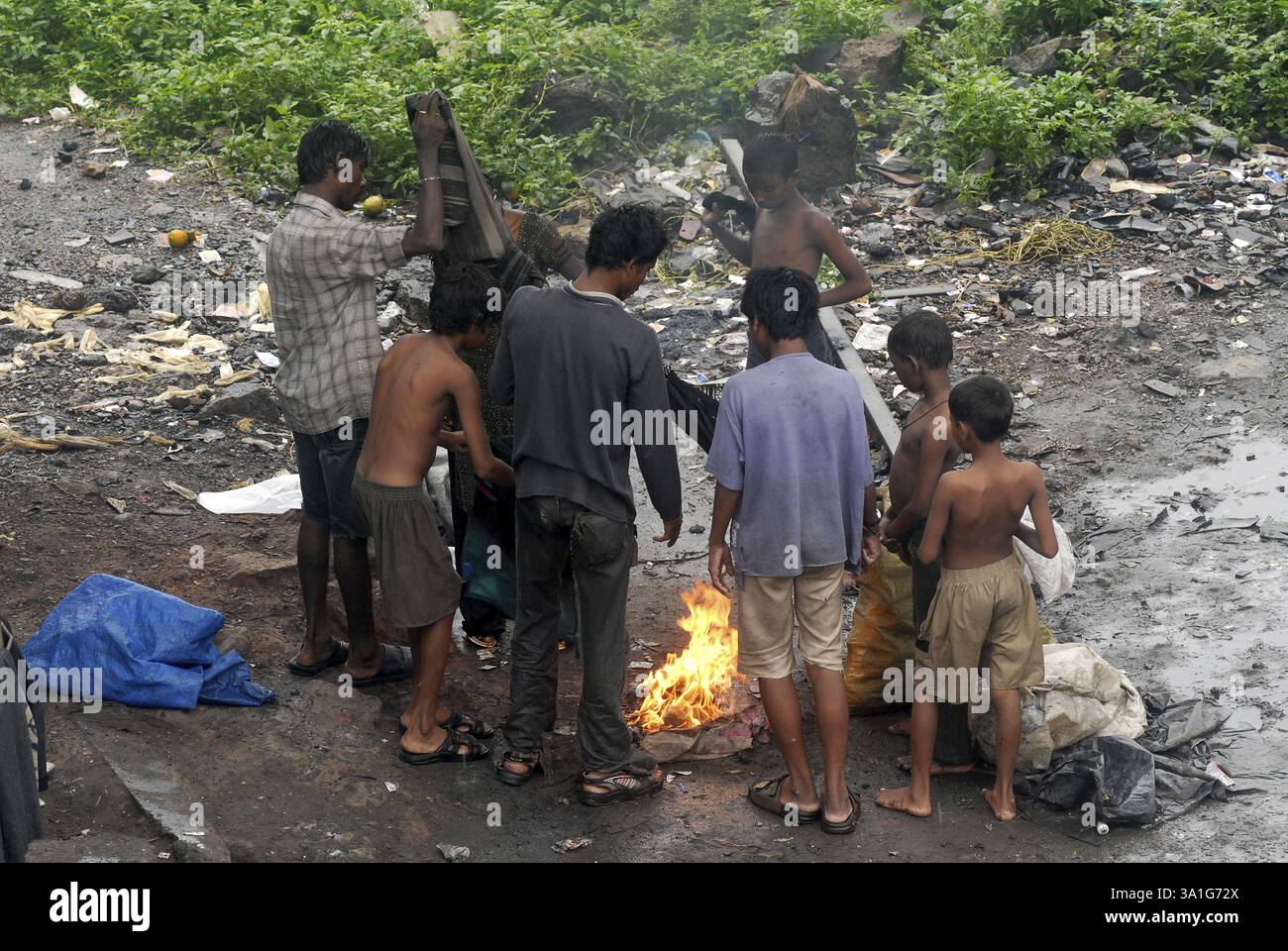 Slum dwellers staying beside the railway tracks make a bon fire to dry ...
