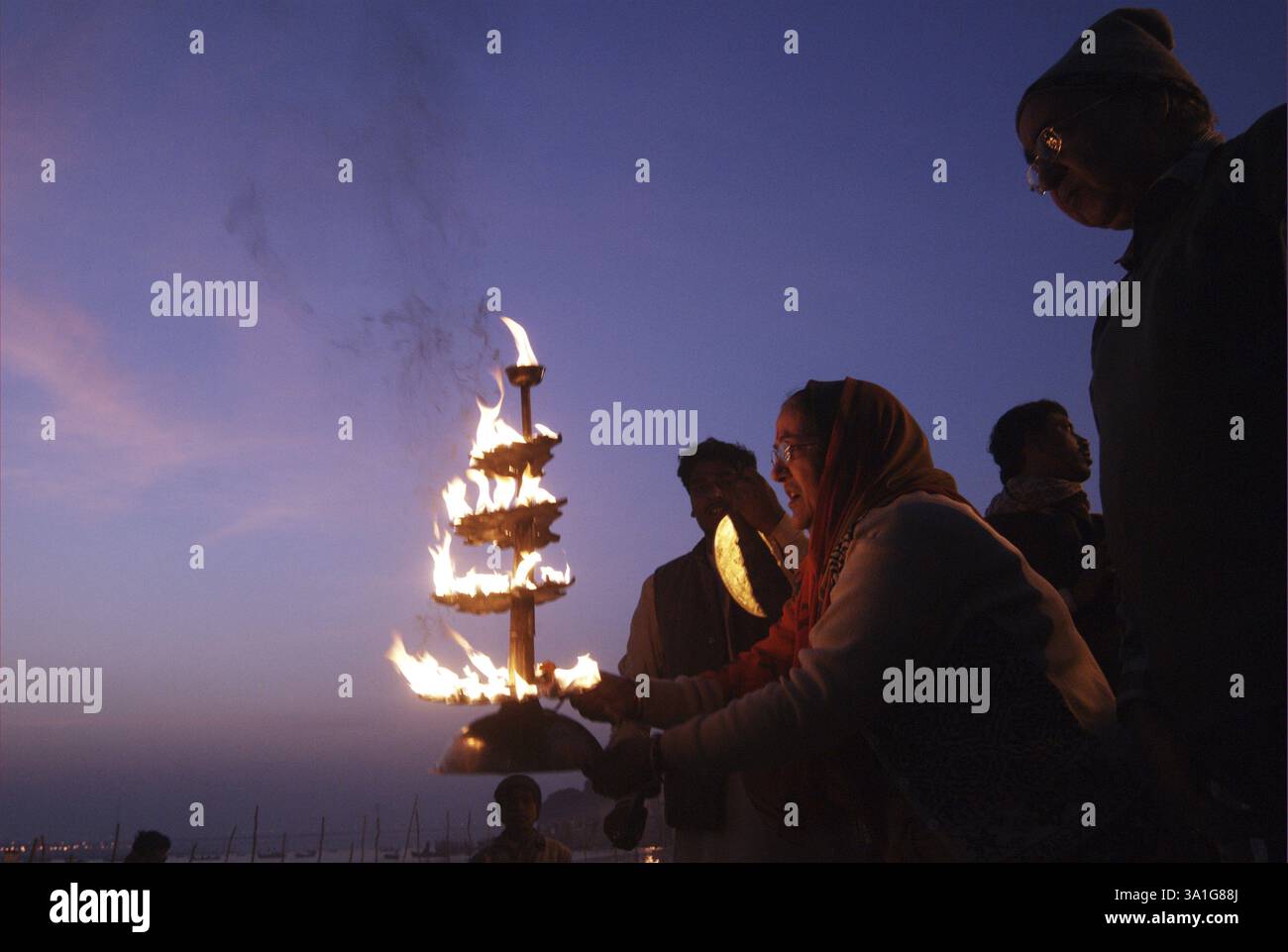 A devotee perform Ganga Aarti at the confluence of the Ganges, Yamuna ...