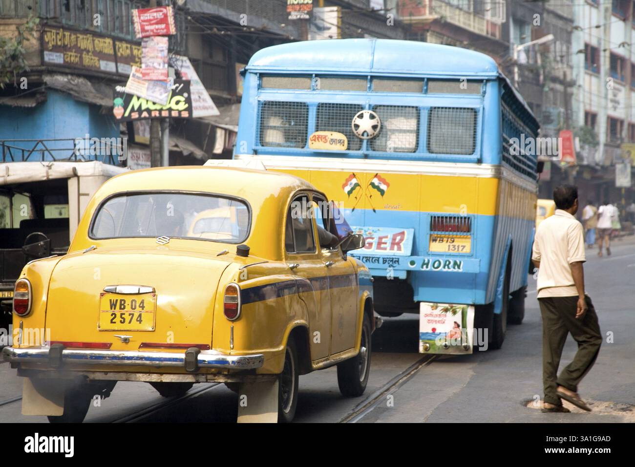 Street scene, yellow color taxi behind blue bus, Calcutta now Kolkata ...