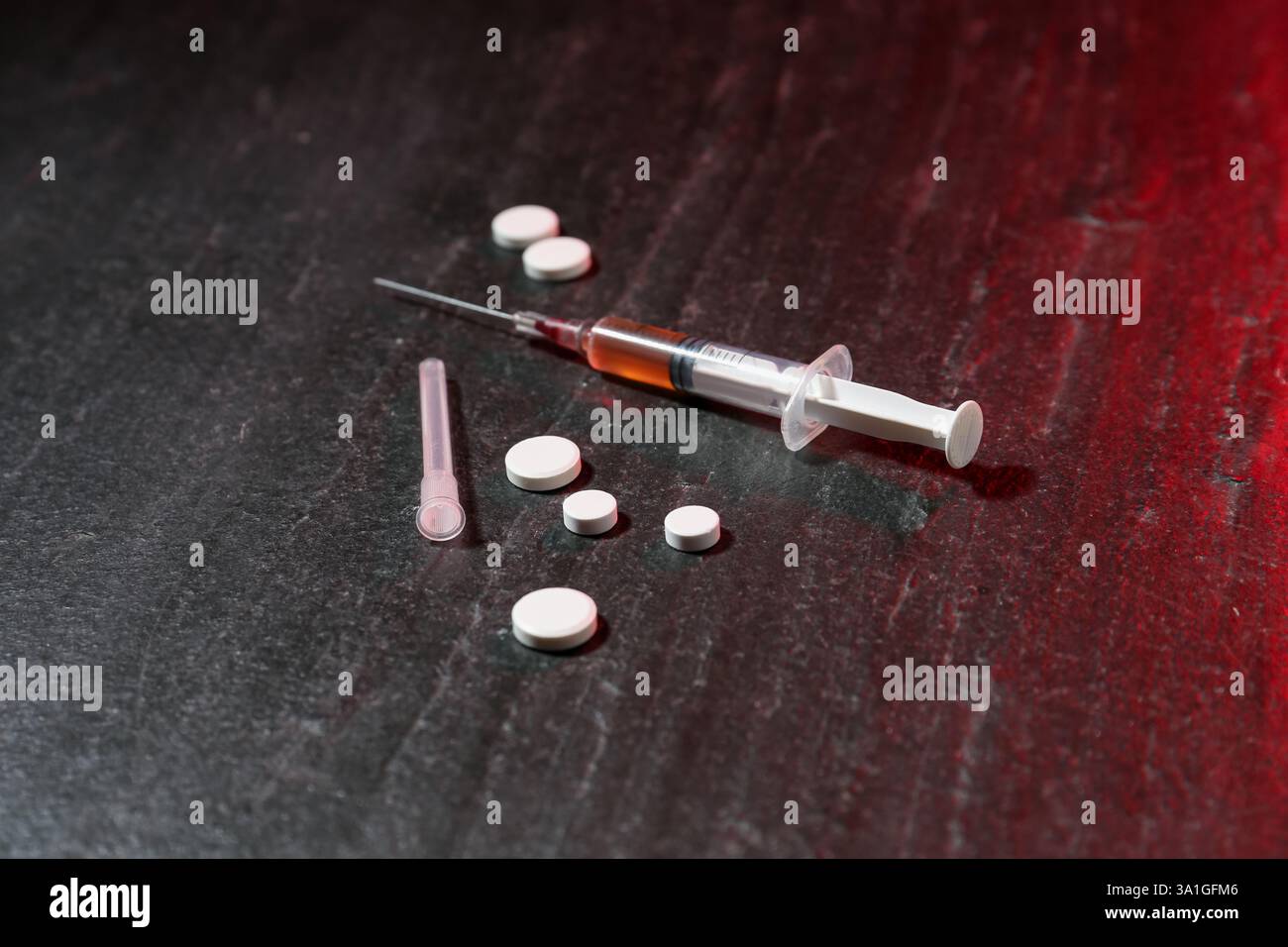 Drug addiction. Syringe and pills on dark textured table in color light ...