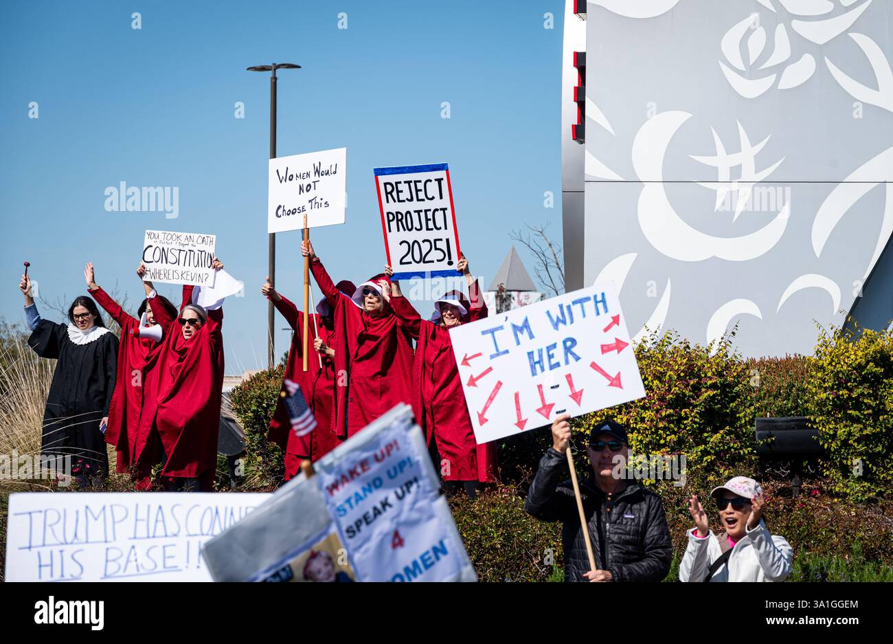 Protesters in red Handmaid's Tale and judge costumes hold signs about ...