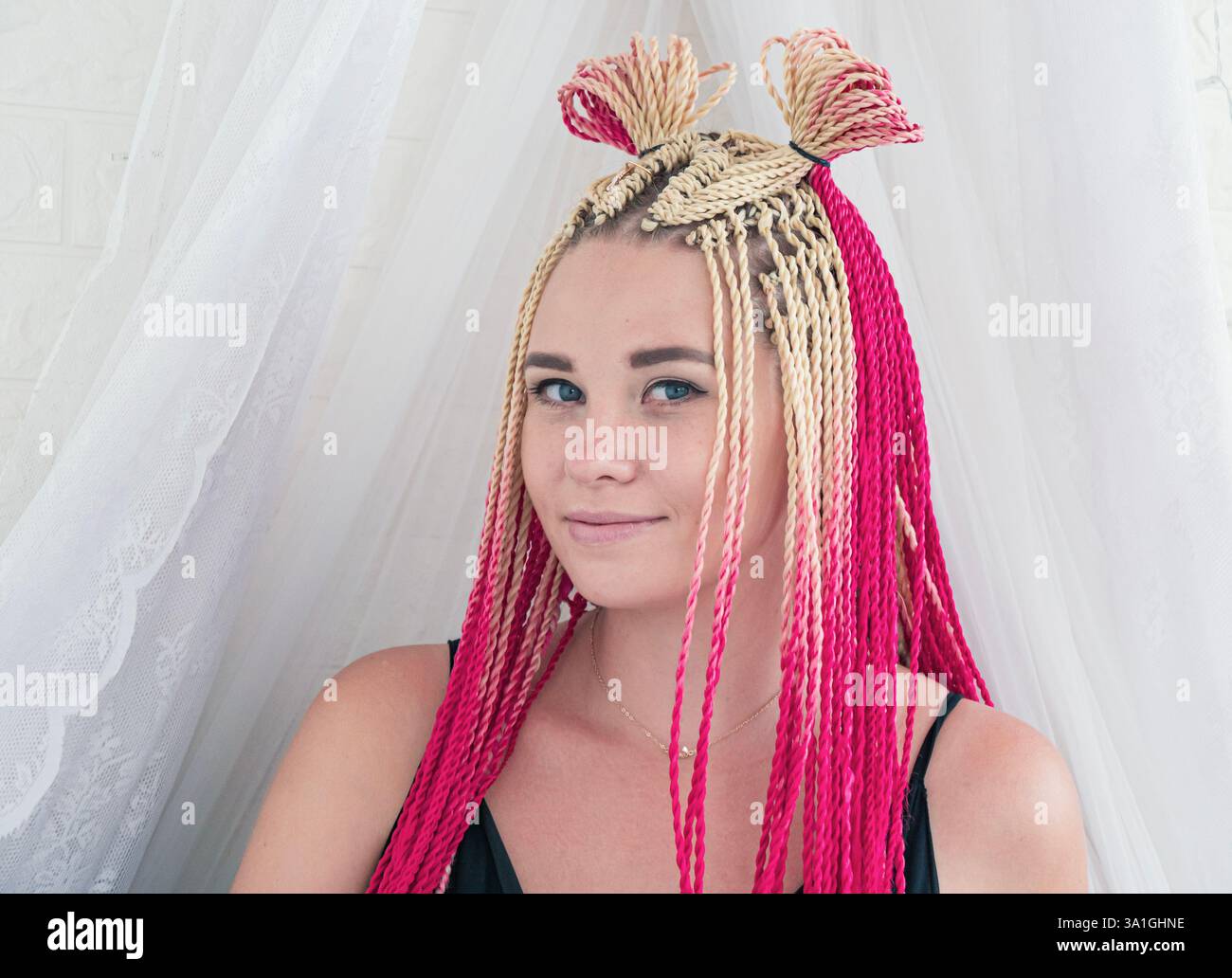 A young woman smiles , displaying her unique hairstyle with long pink ...