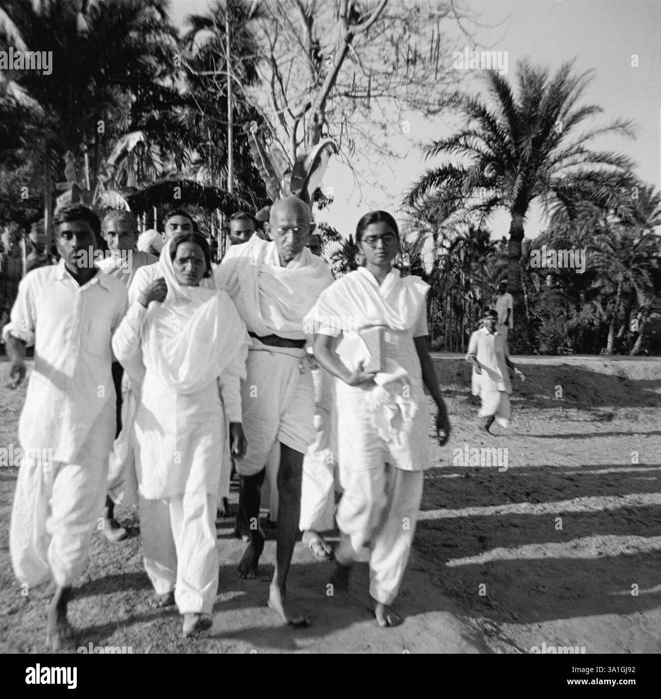 Mahatma Gandhi, supported by Amtus Salam and Manu Gandhi, walking with ...