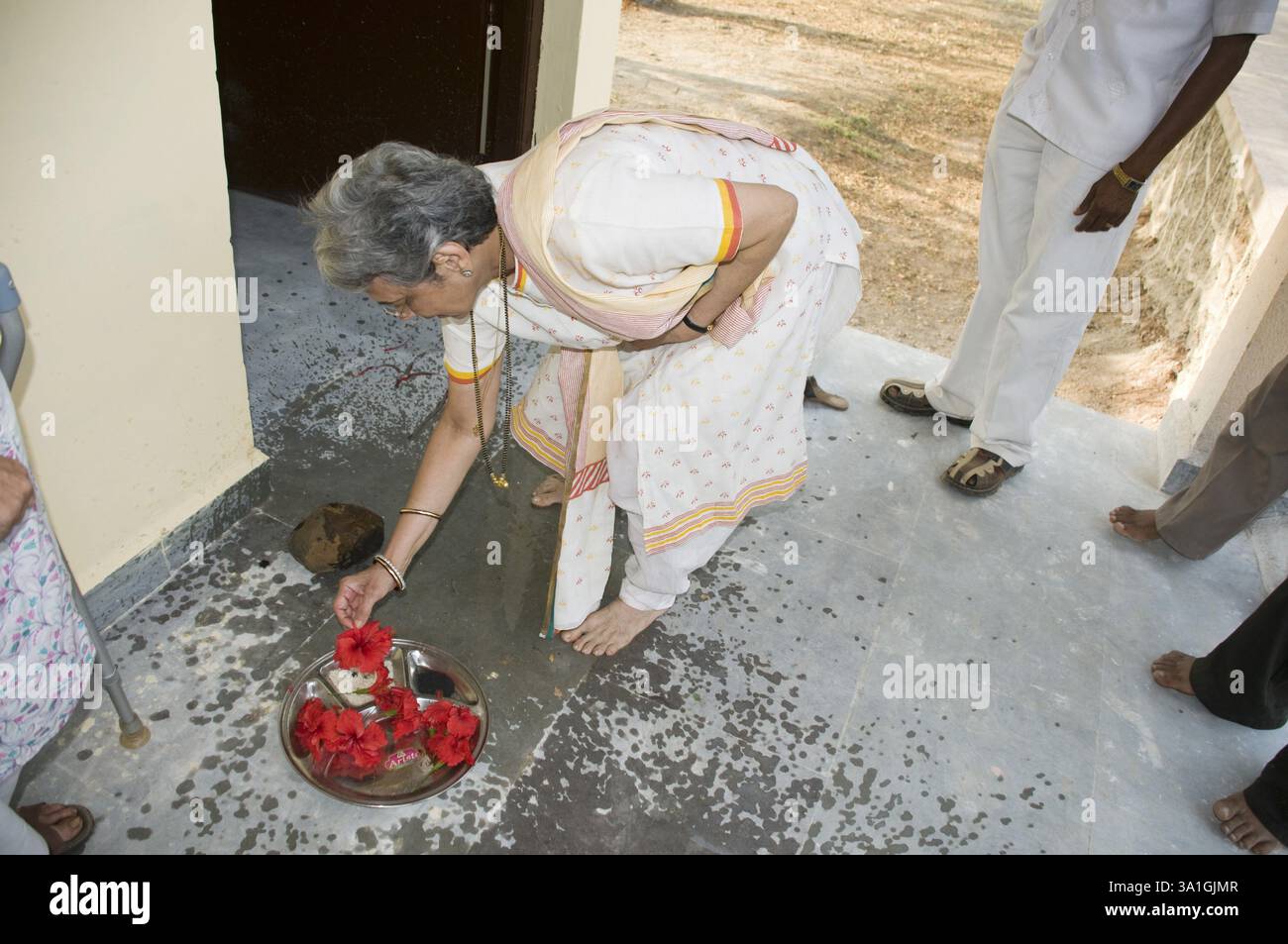 Lady breaking coconut, Shivkar village, Panvel taluka, Maharashtra ...