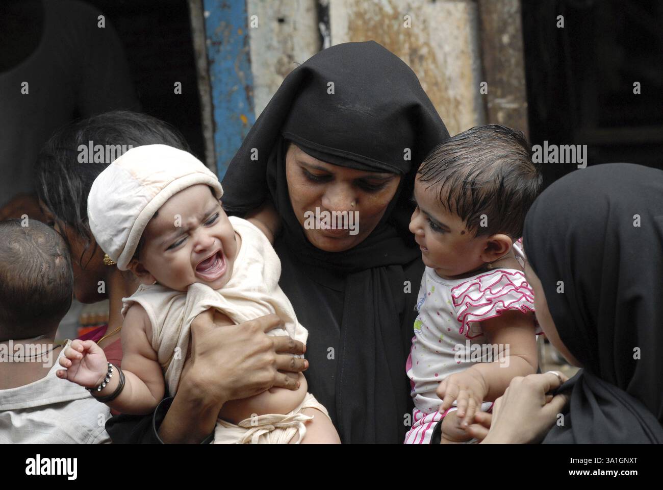 Muslim women stand in a queue with their children at a pulse polio ...