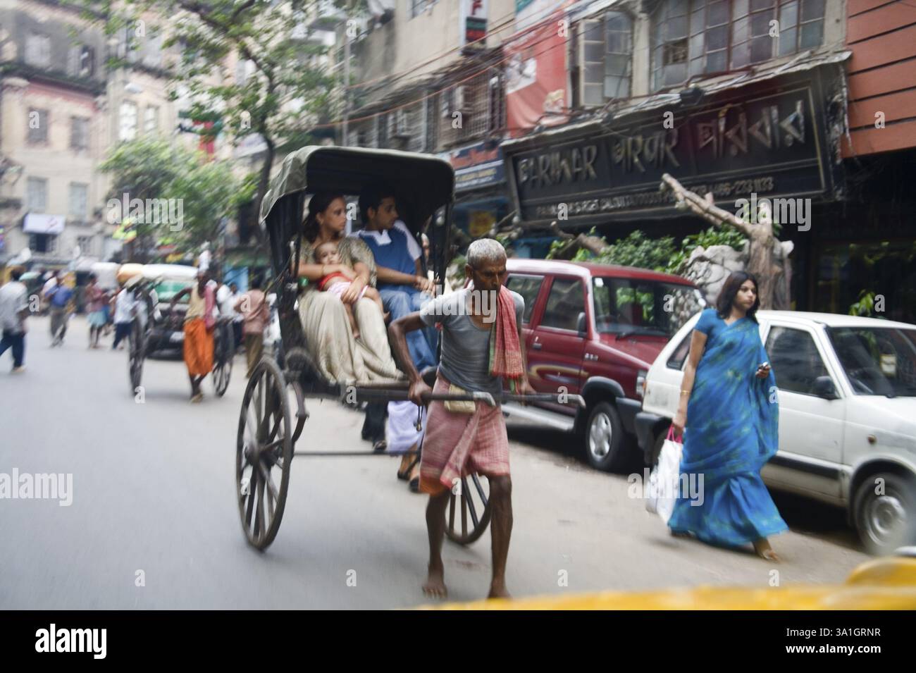 Old man pulling hand rickshaw with passengers, street scene of Calcutta ...