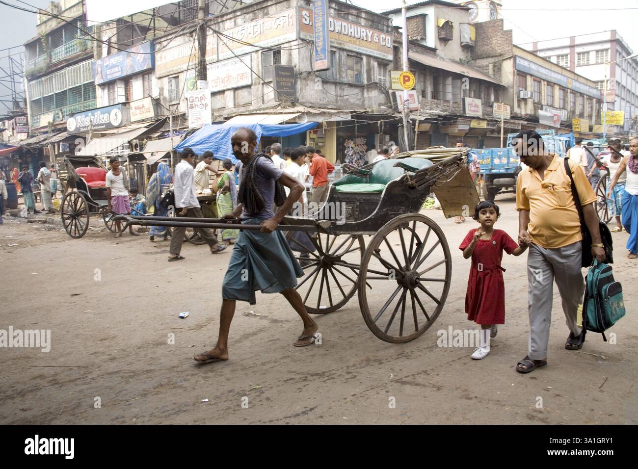 Street scene, hand rickshaw puller pulling empty vehicle on busy street ...