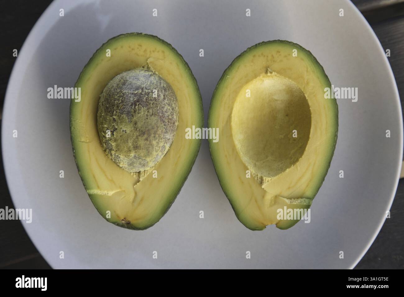 Fruit, avocado cut in half placed in plate with seed Common name ...