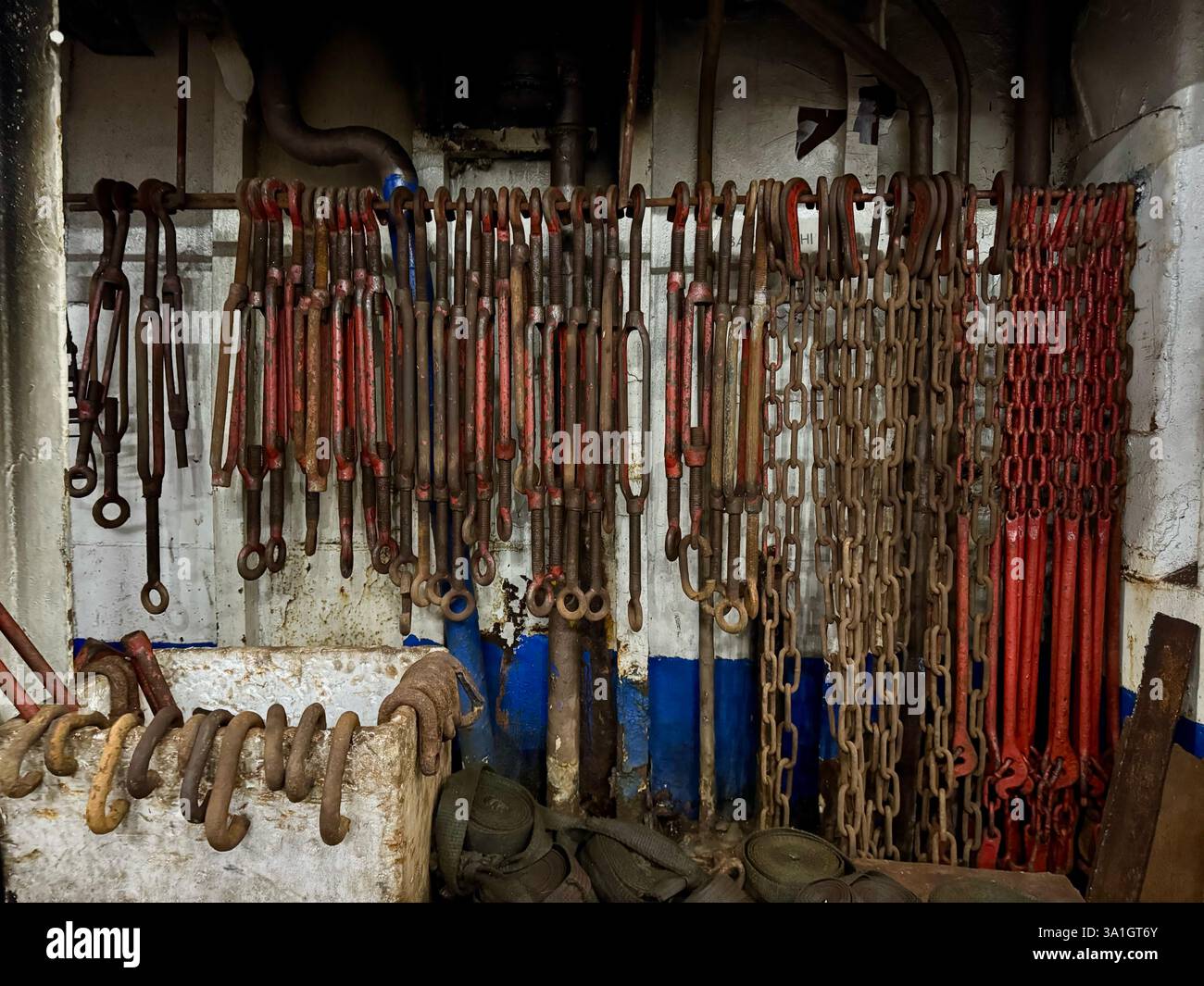 Rusty chains and metal turnbuckles hanging in an old industrial storage ...