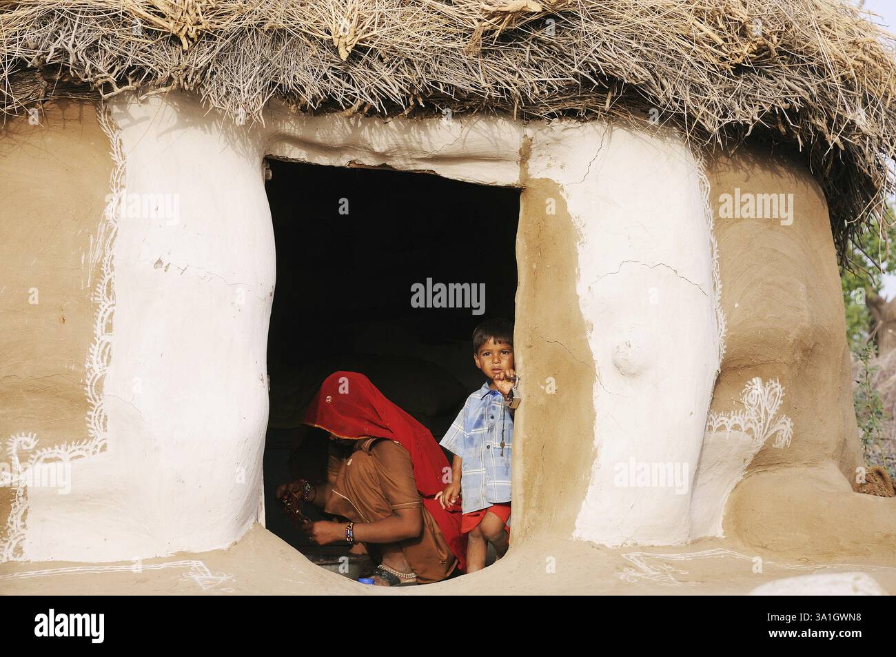 Rural Rajasthani lady sitting inside hut with her child, Sujangarh ...
