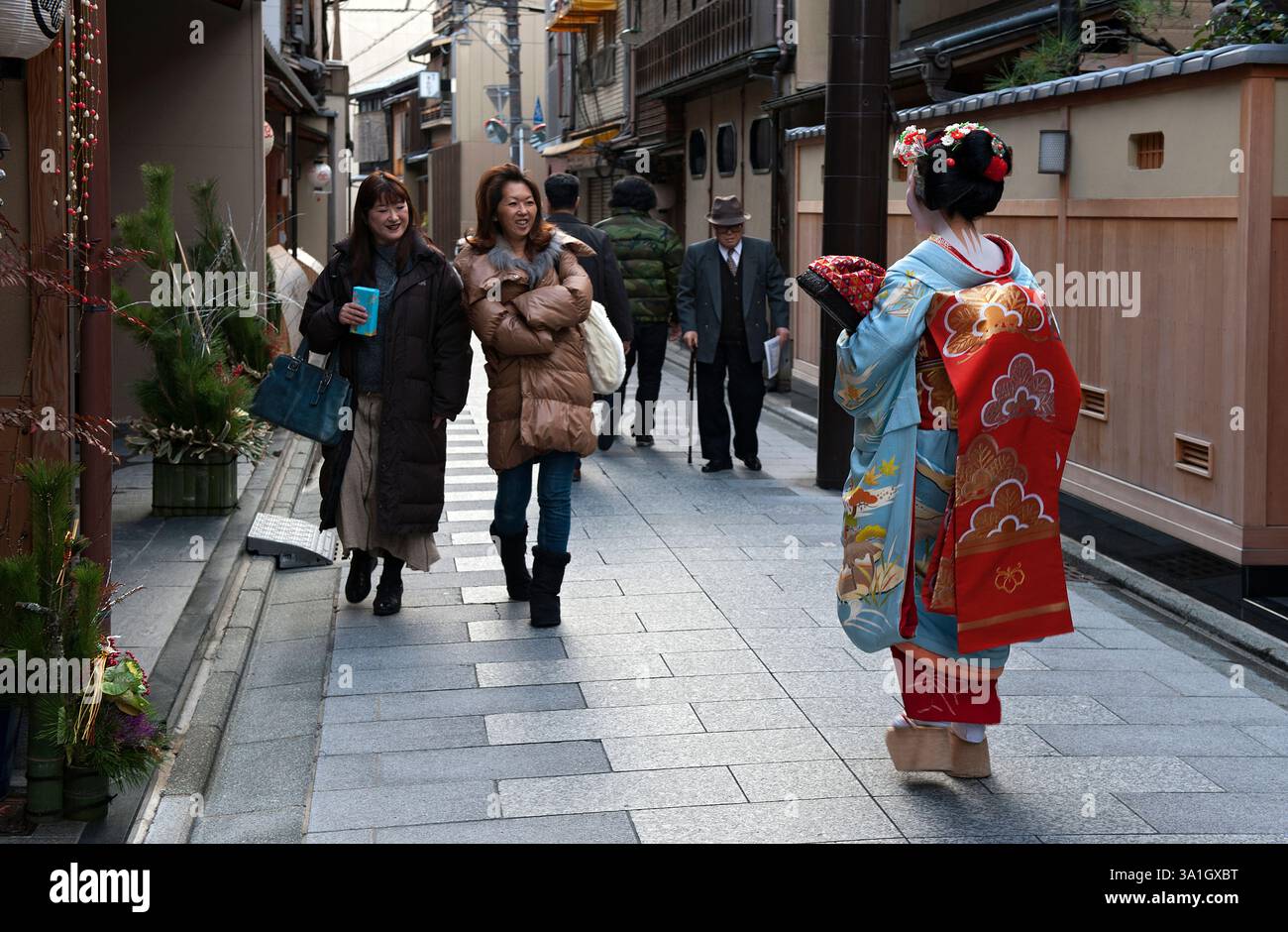 A Japanese maiko, or apprentice geisha or geiko, walking along a ...