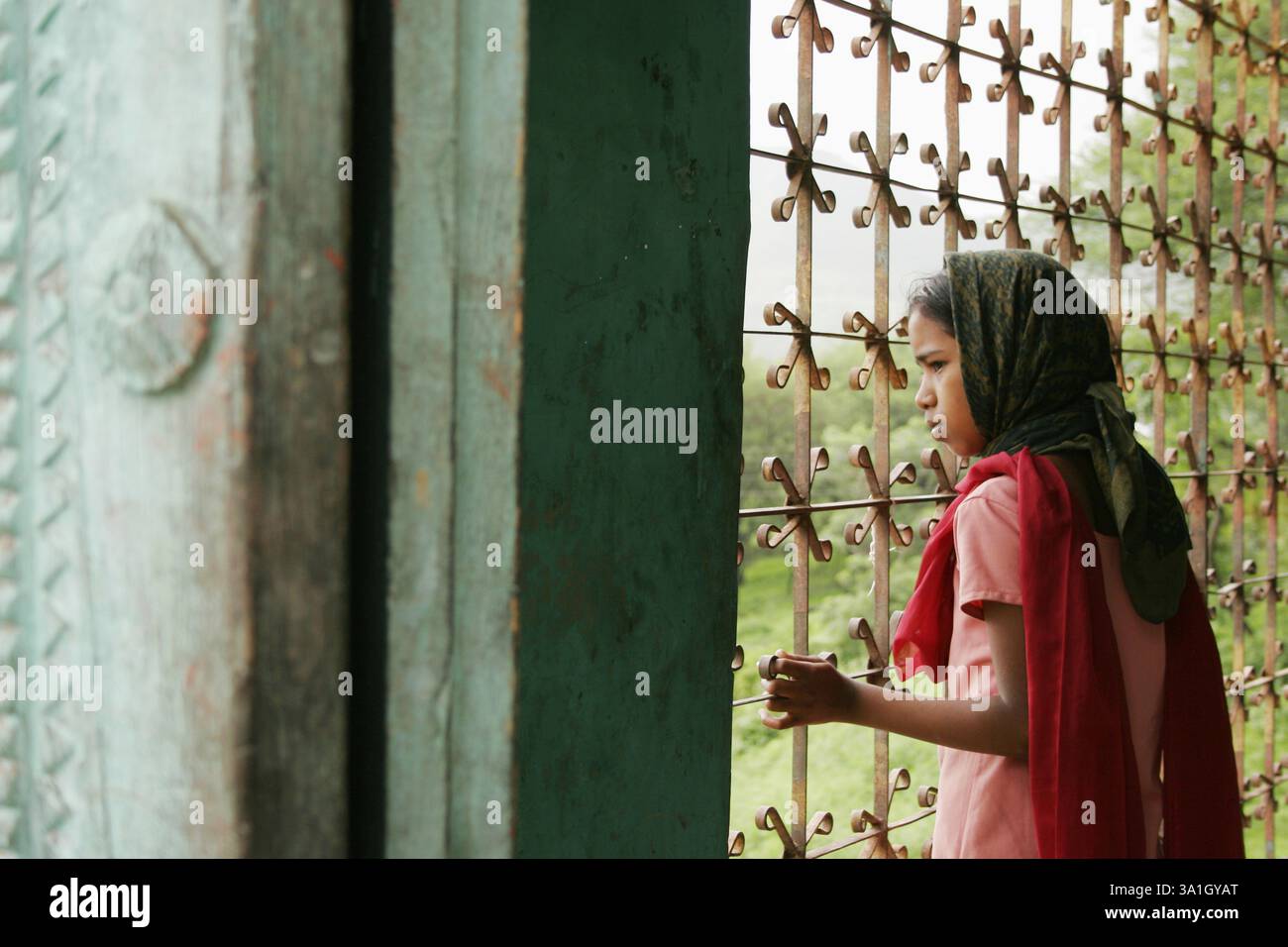 Maharashtrian girl standing in a room against an iron window grill ...