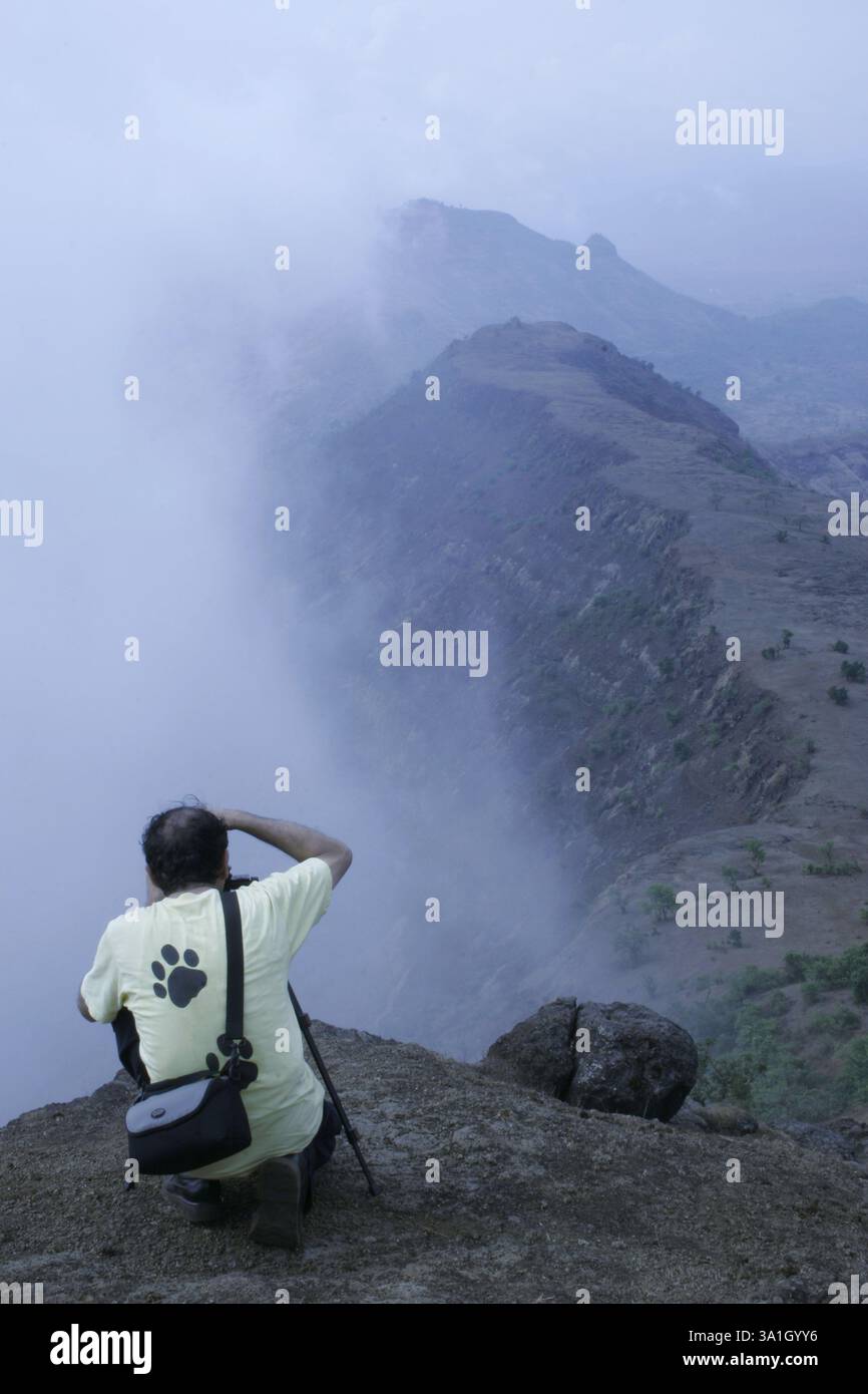 A photographer taking a picture of a landscape with monsoon clouds ...
