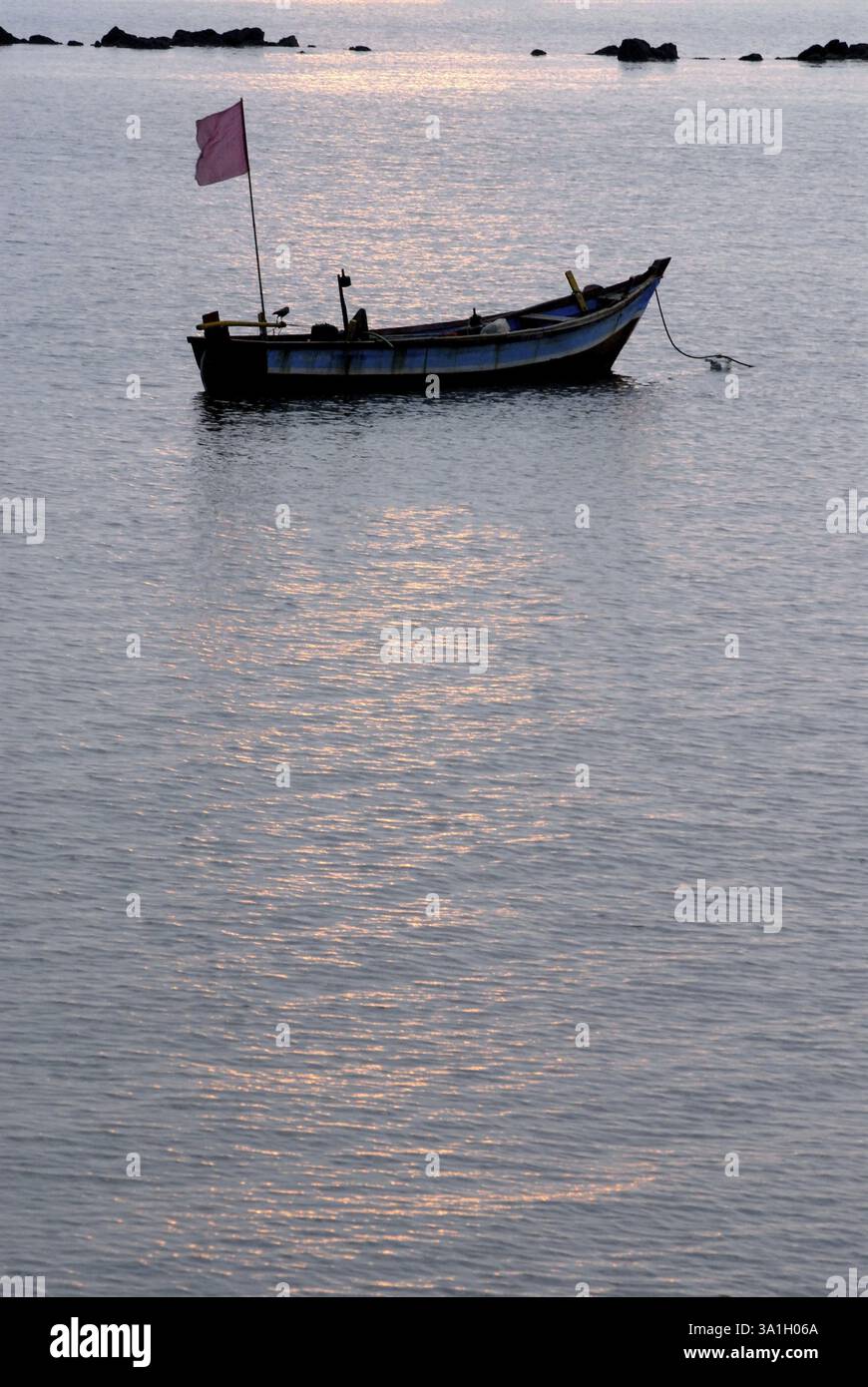 Sparkling sea water at sunset with small country fishing boat at Malvan ...