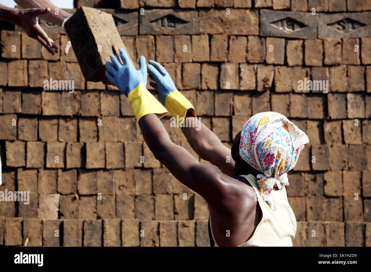A worker handing over a brick at the brick factory in a village of ...