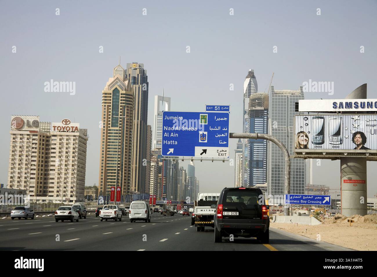 Blue sign boards on road for direction with traffic and high rise ...