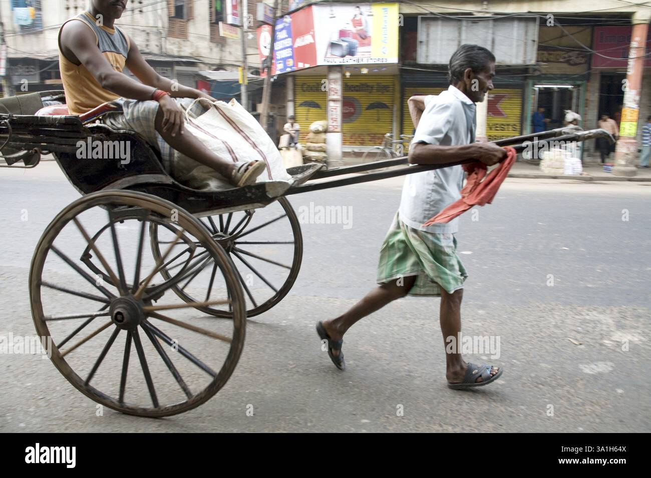 Manual labor hand rickshaw puller pulling with passenger, Calcutta now ...