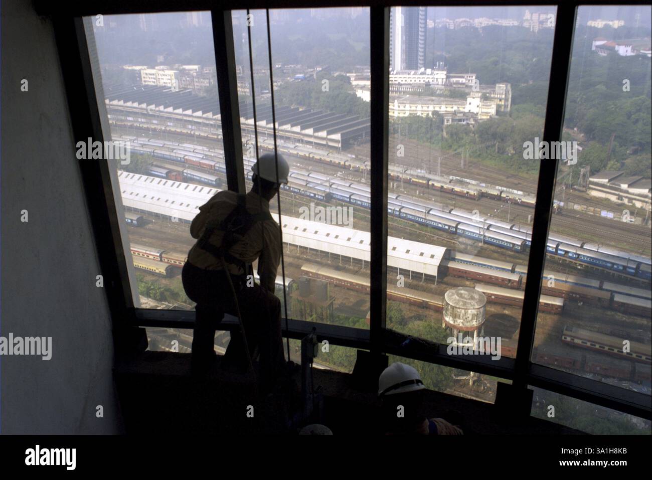 Worker cleaning glass of high-rise tower situated near the railway ...