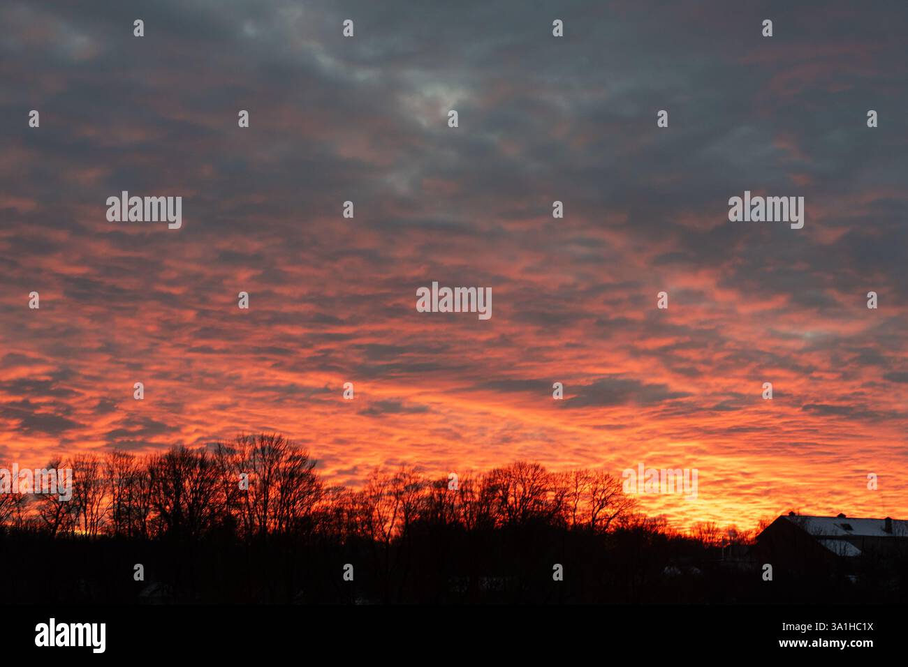 A dramatic sunset with red highlights through dark clouds, illuminating ...