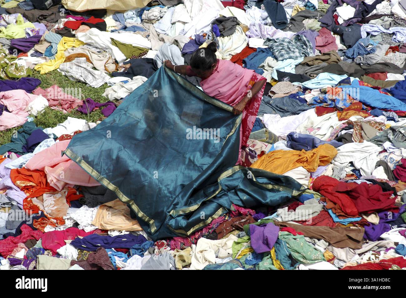 A woman checking the saree before taking it from the stacks of clothes ...