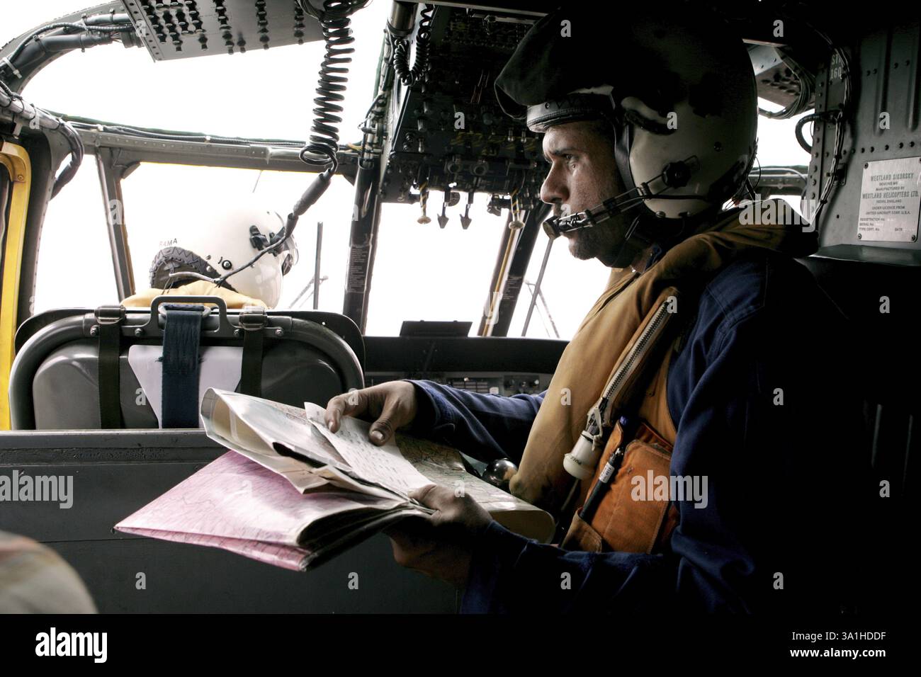 Indian Navy helicopter navigator sitting with maps of area navigating ...