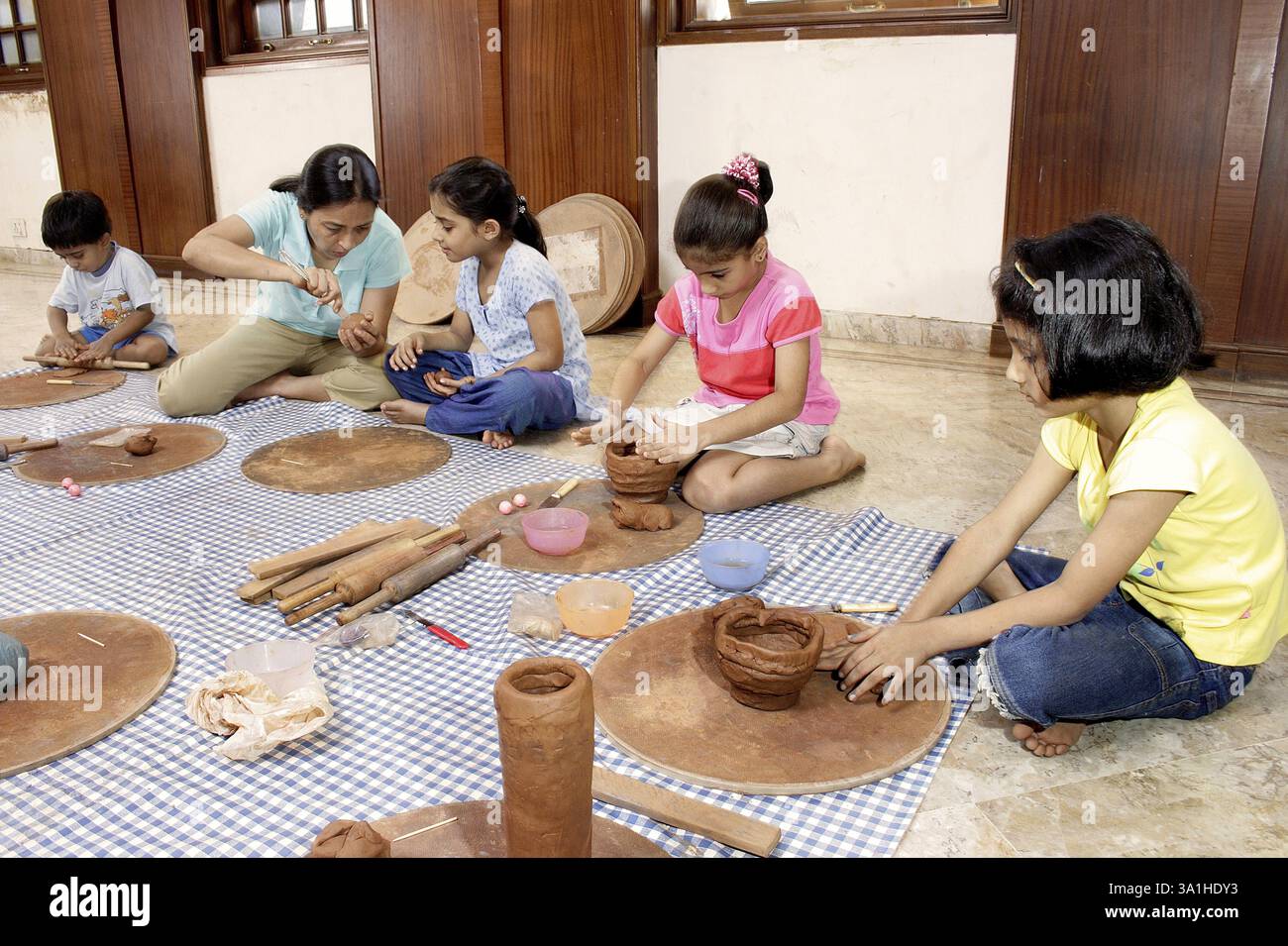 Pottery class for children, potter teaching children how to make pot on wheel with other ...