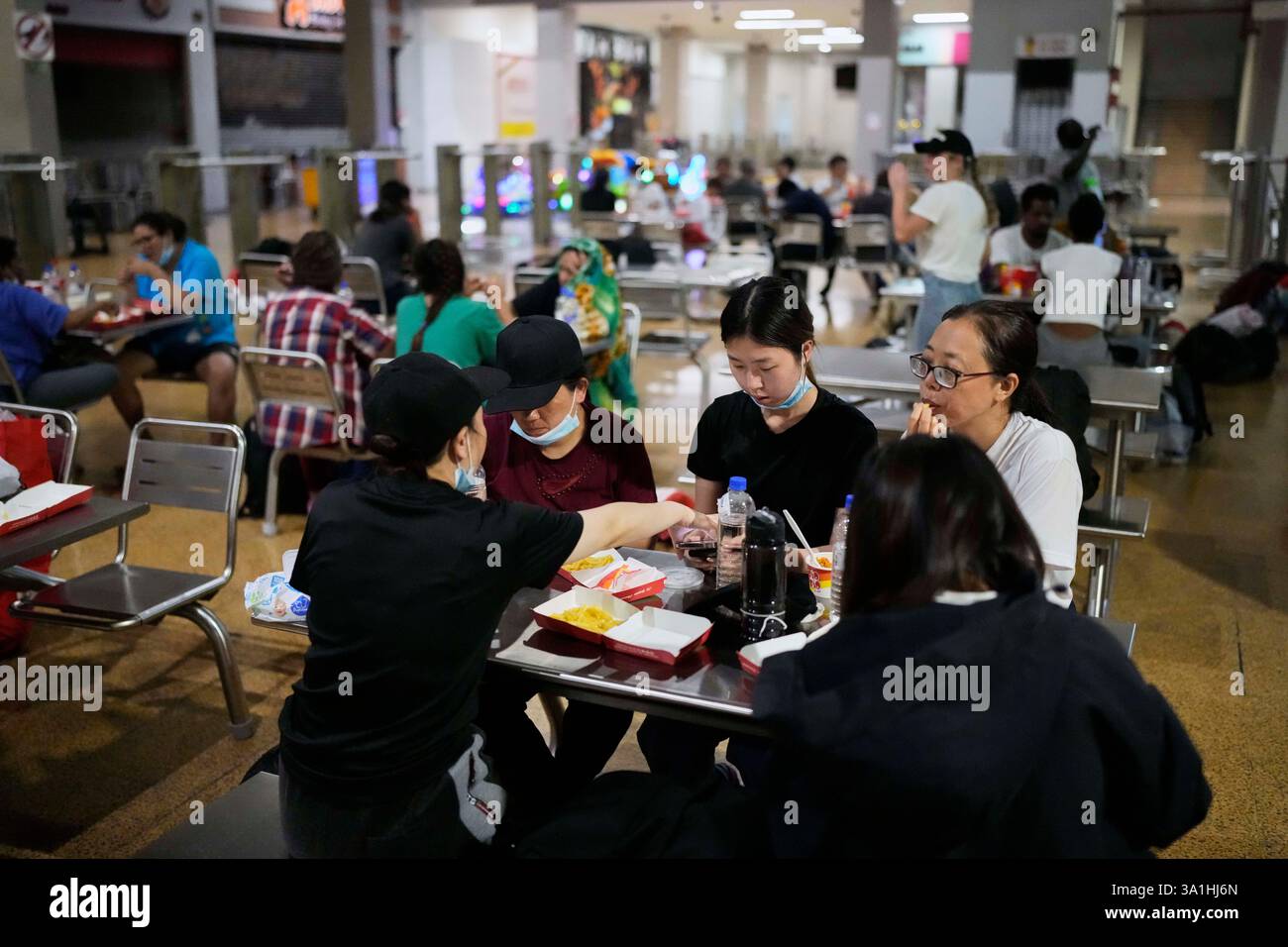 Chinese migrants eat at a bus station food court after arriving in ...