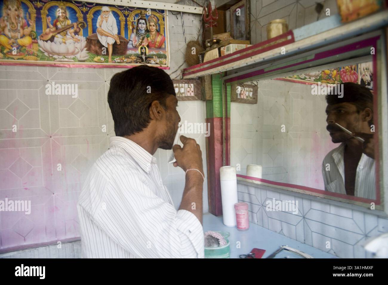 One man cutting his moustache in barber shop decorated with pictures of ...