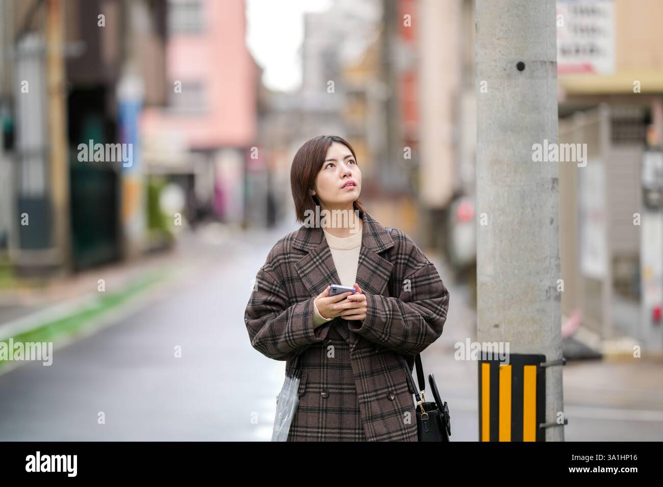 A 29-year-old Japanese woman wearing a checkered coat. She walks ...