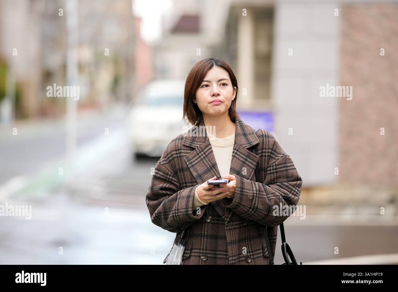 A 29-year-old Japanese woman wearing a checkered coat. She walks ...