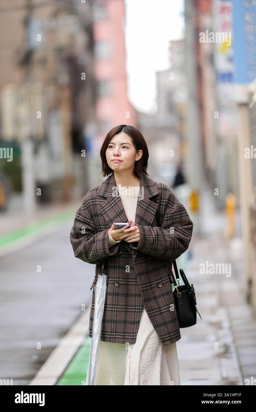 A 29-year-old Japanese woman wearing a checkered coat. She walks ...