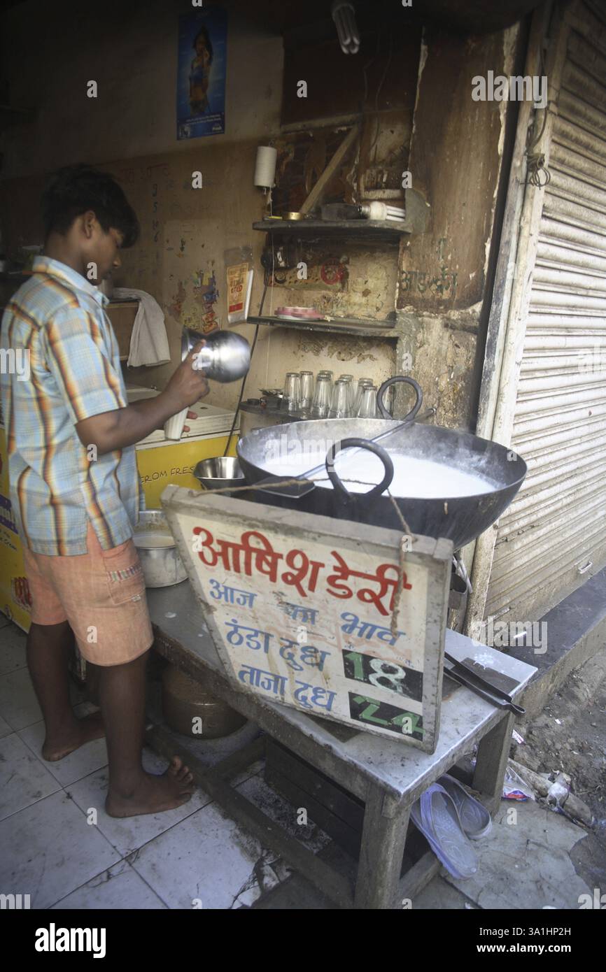 Milk boiling in big black pot and man pouring in glass form pot, milk ...